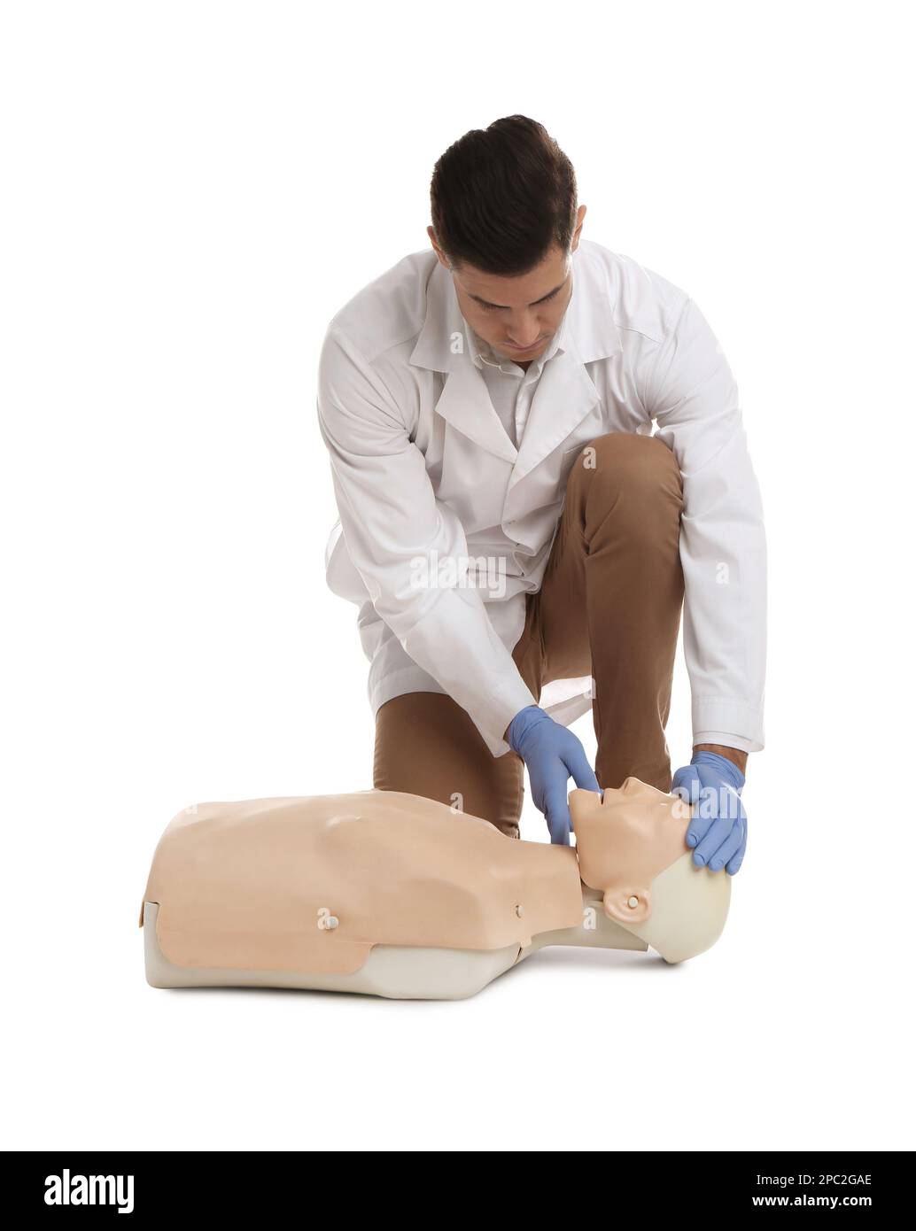 Doctor in uniform practicing first aid on mannequin against white ...
