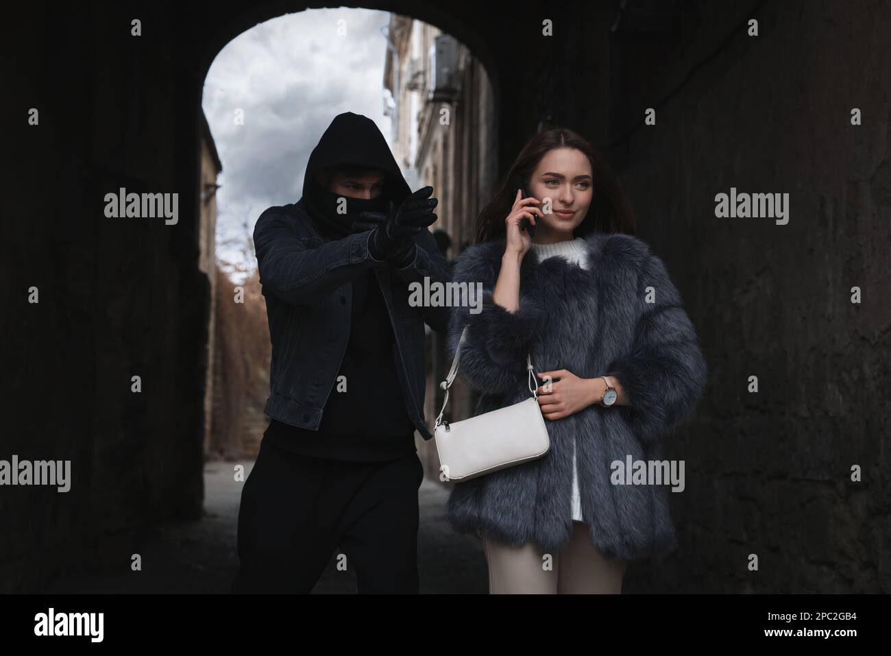 Criminal attacking young woman while she talking on phone in alley ...