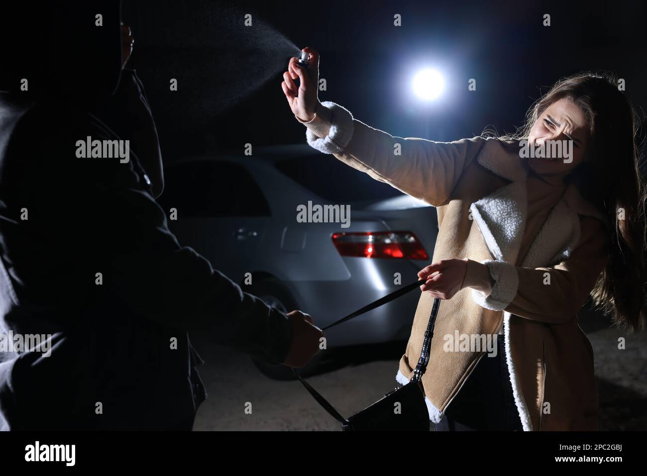 Woman using pepper spray while thief trying to steal her bag outdoors ...