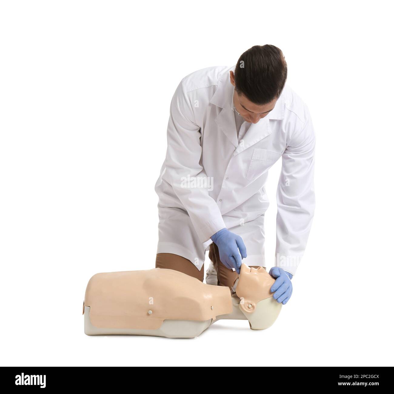 Doctor in uniform practicing first aid on mannequin against white ...