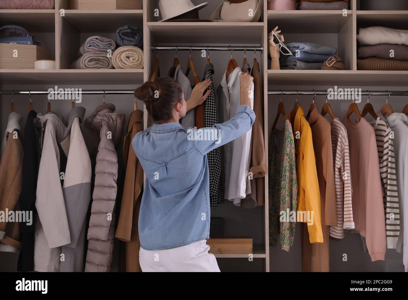 Young woman choosing clothes in wardrobe closet, back view Stock Photo ...