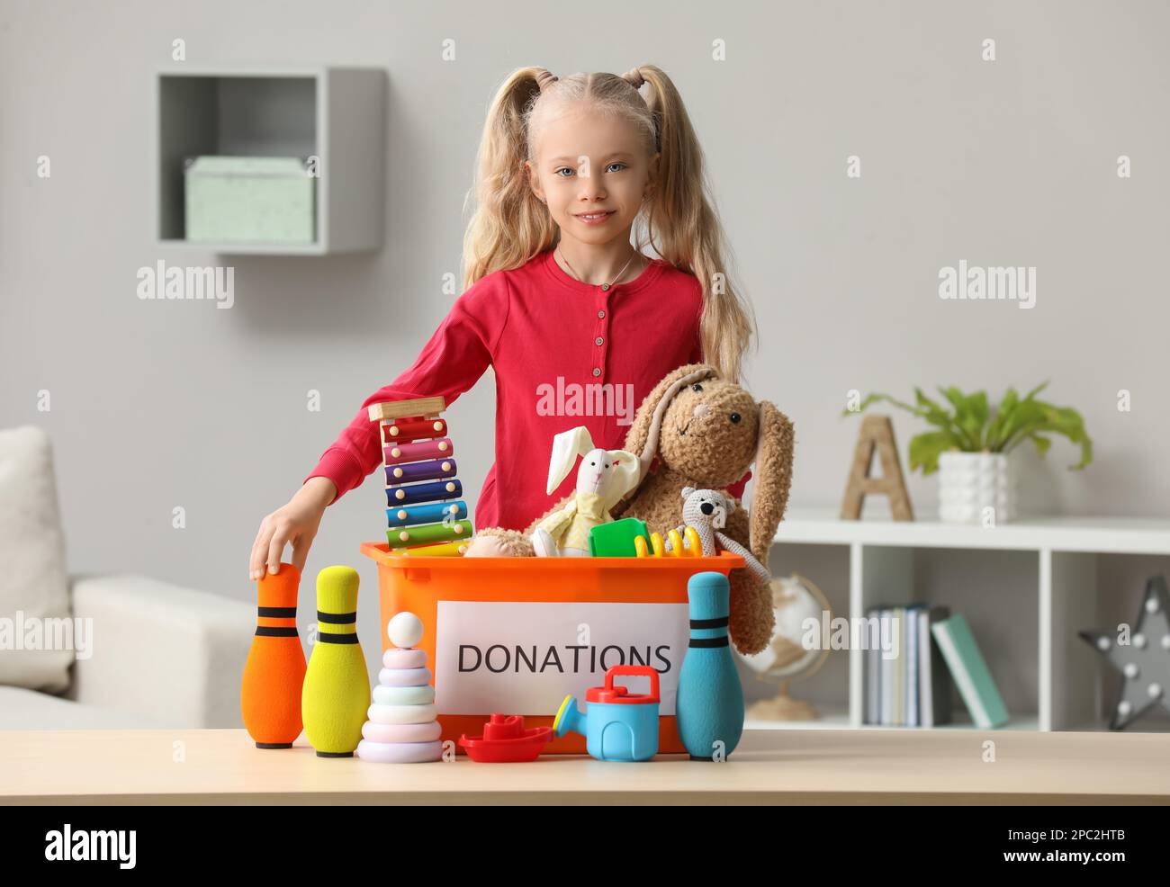 Cute little girl sorting donation box at home Stock Photo - Alamy