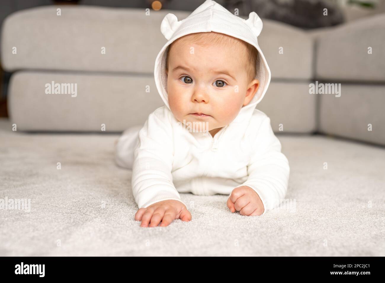 childhood, babyhood and people concept - happy little baby boy or girl lying on floor at home ...
