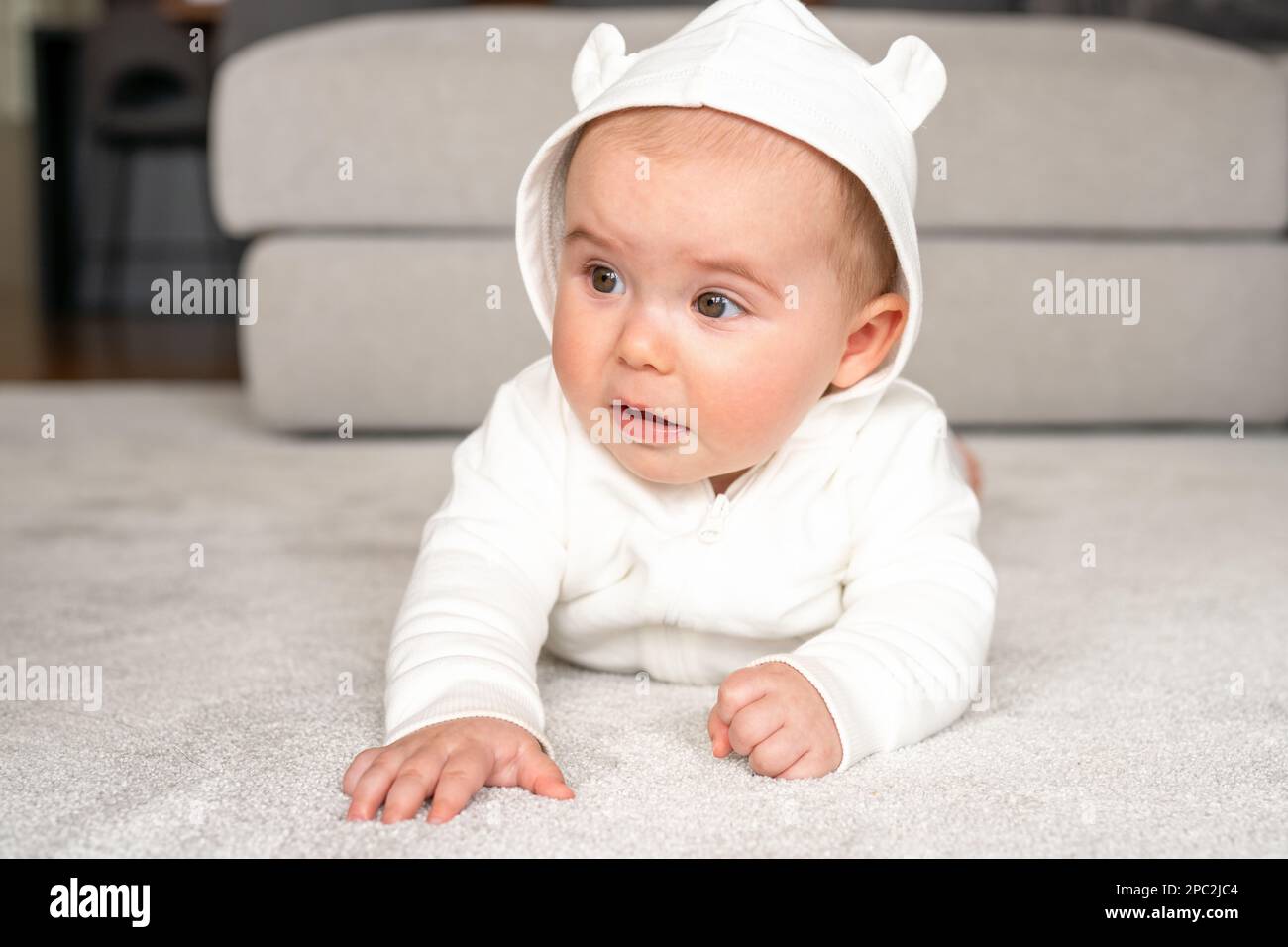 childhood, babyhood and people concept - happy little baby boy or girl lying on floor at home ...