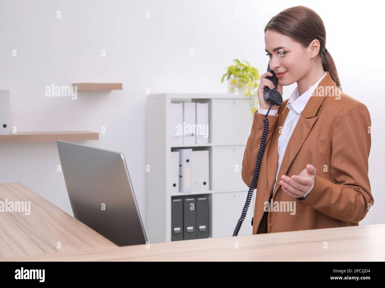 Female receptionist talking on phone at workplace Stock Photo - Alamy