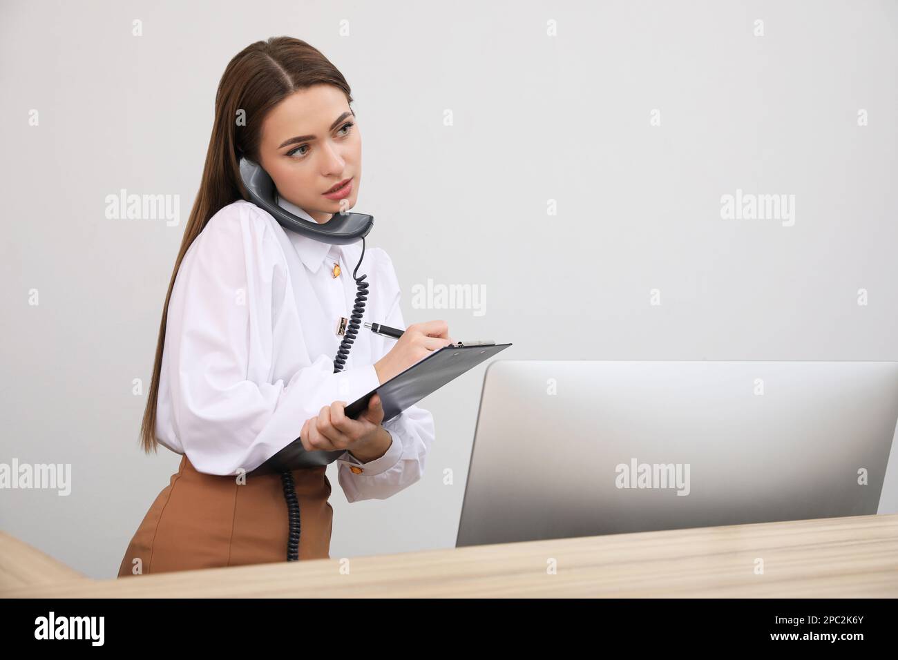 Female receptionist with clipboard talking on phone at workplace Stock ...