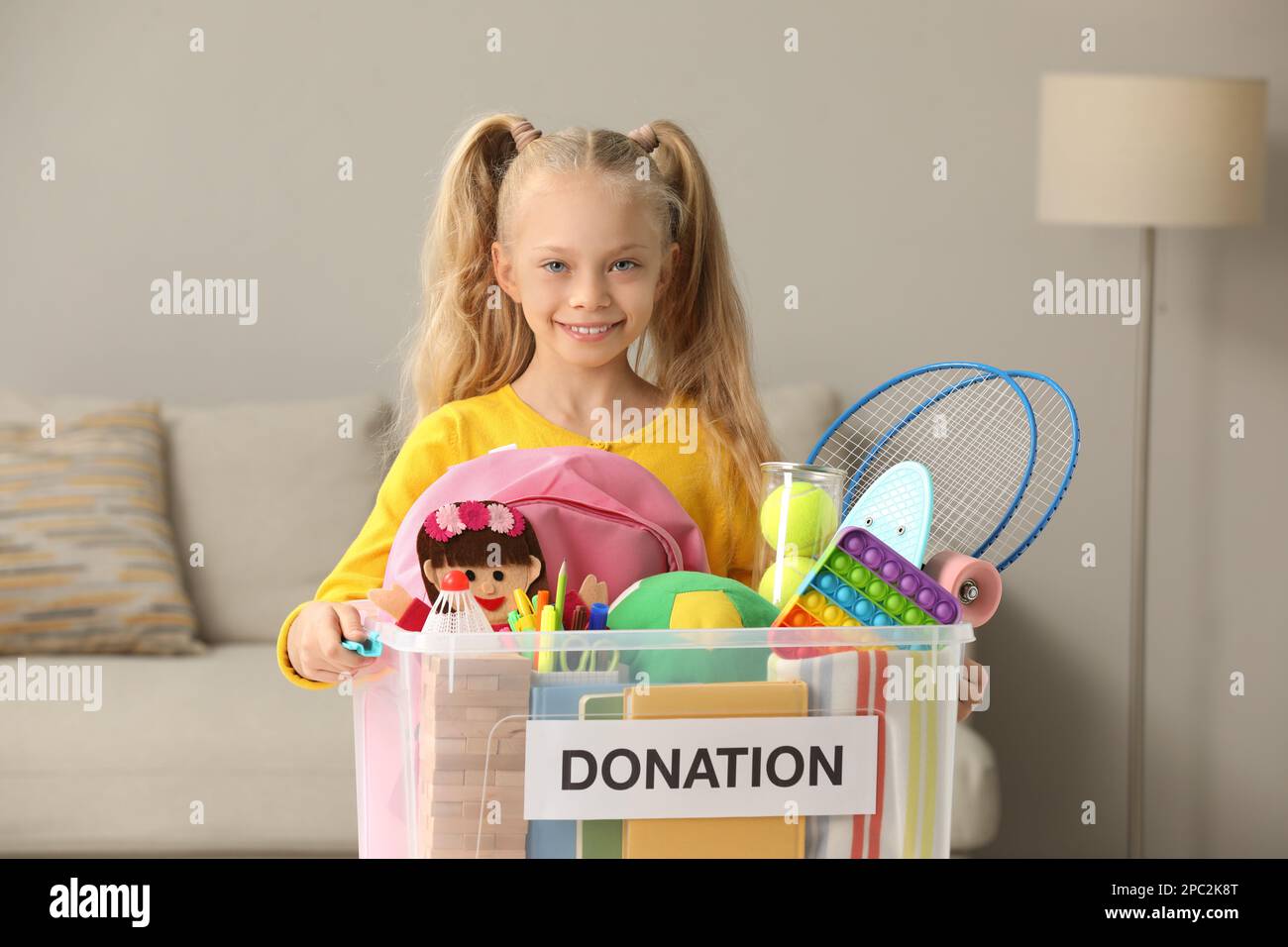 Cute little girl holding donation box with toys at home Stock Photo - Alamy