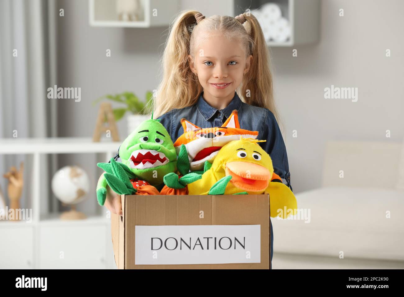 Cute little girl holding donation box with soft toys at home Stock Photo - Alamy