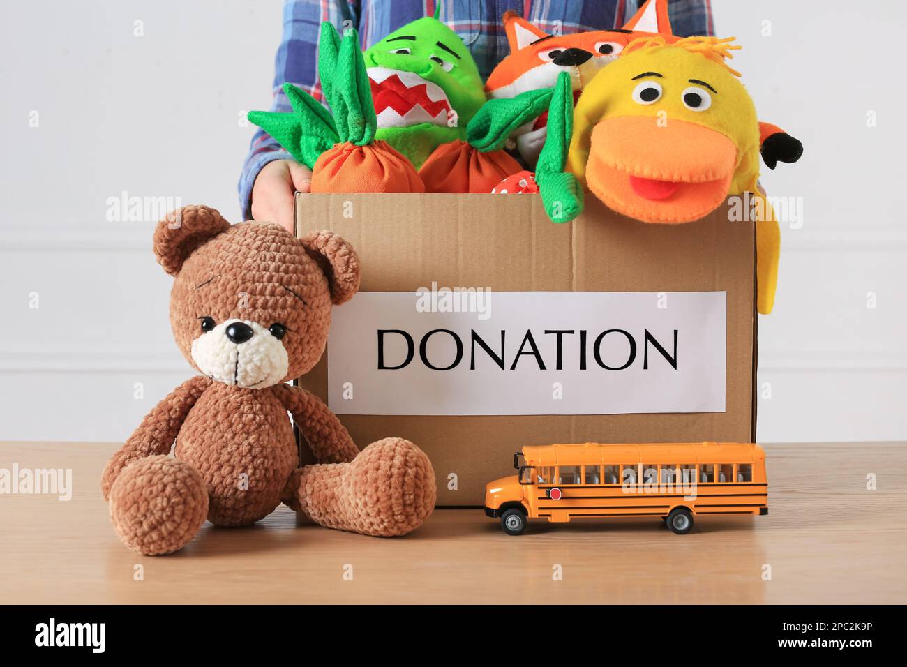 Little boy holding donation box with toys against white background ...