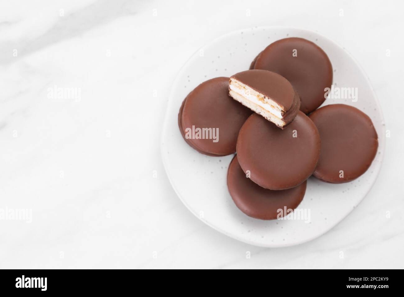 Saucer with delicious choco pies on white table, top view. space for ...