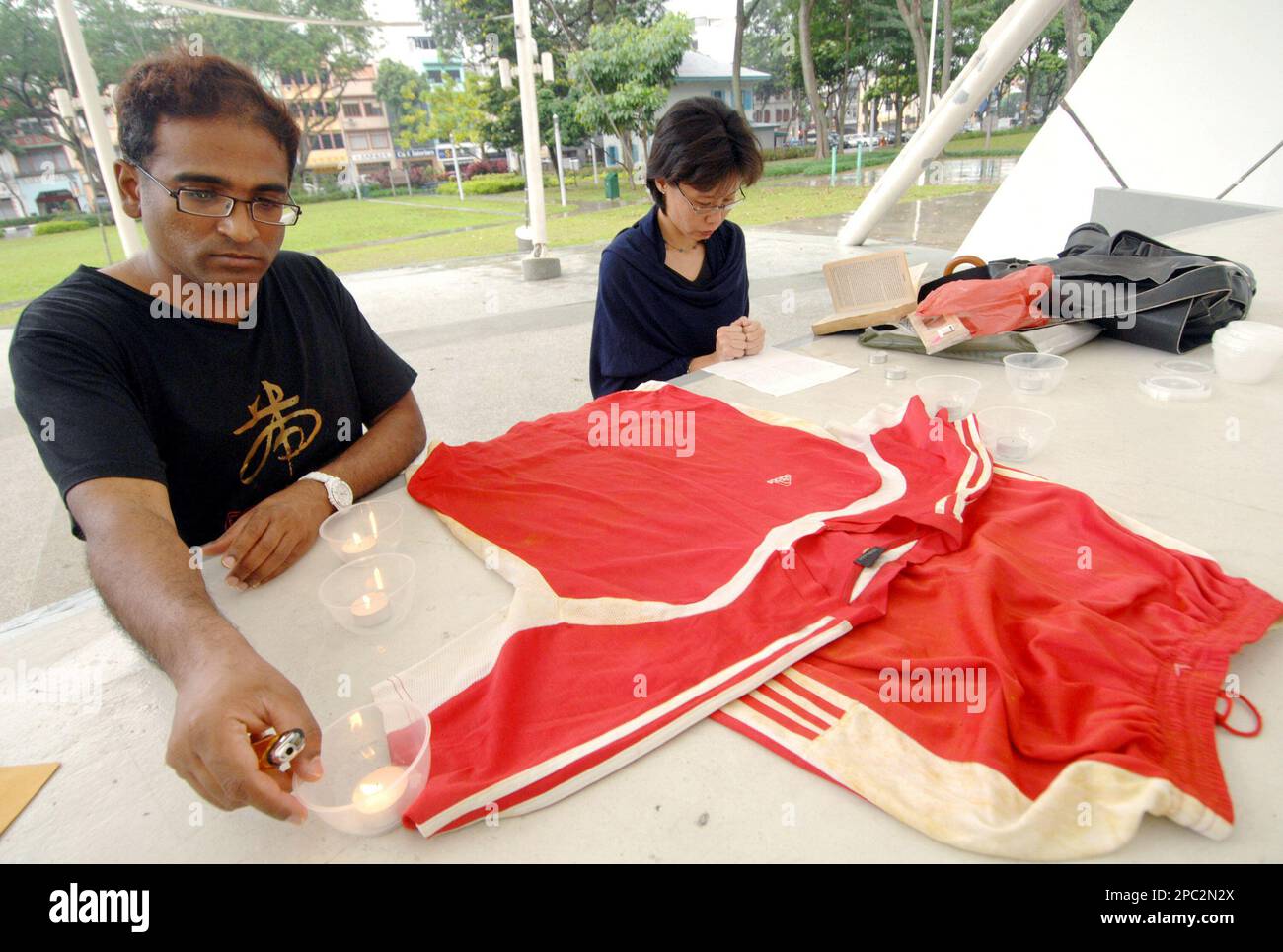 M. Ravi, left, lights candles around a football jersey belonging to ...