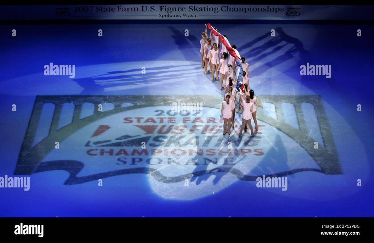 Figure skaters carry the U.S. flag off the ice during opening ...