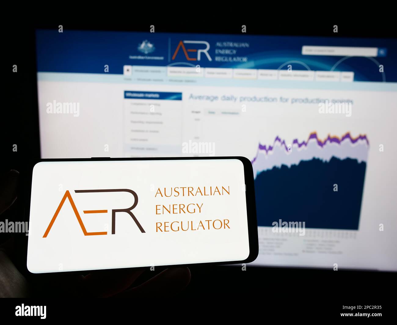 Person holding mobile phone with logo of authority Australian Energy ...