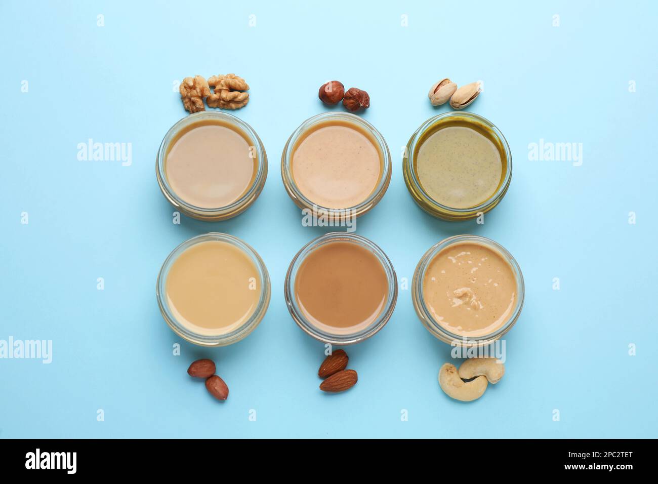 Different types of delicious nut butters and ingredients on light blue ...