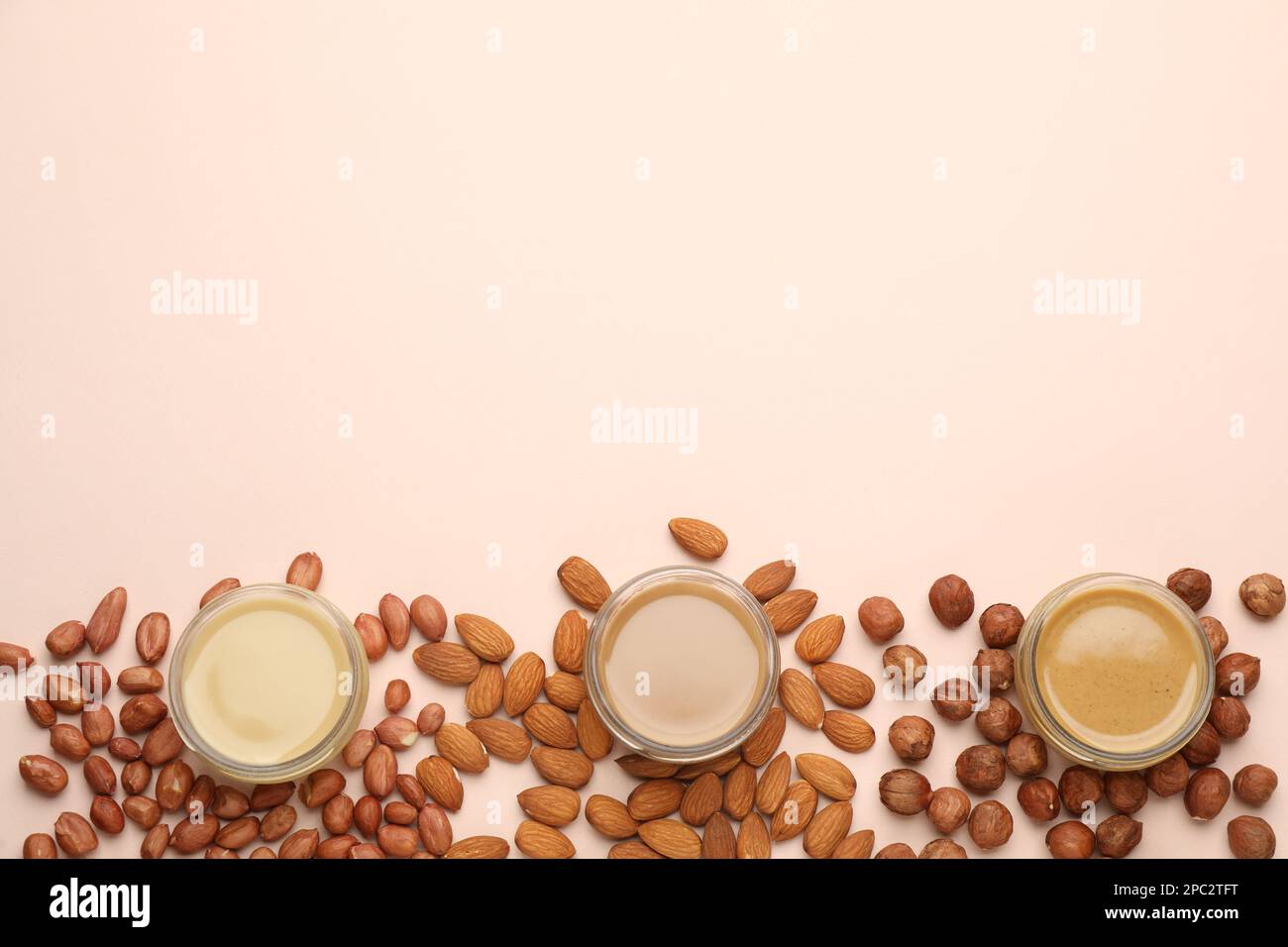 Different Types Of Delicious Nut Butters And Ingredients On Beige Background Flat Lay Space