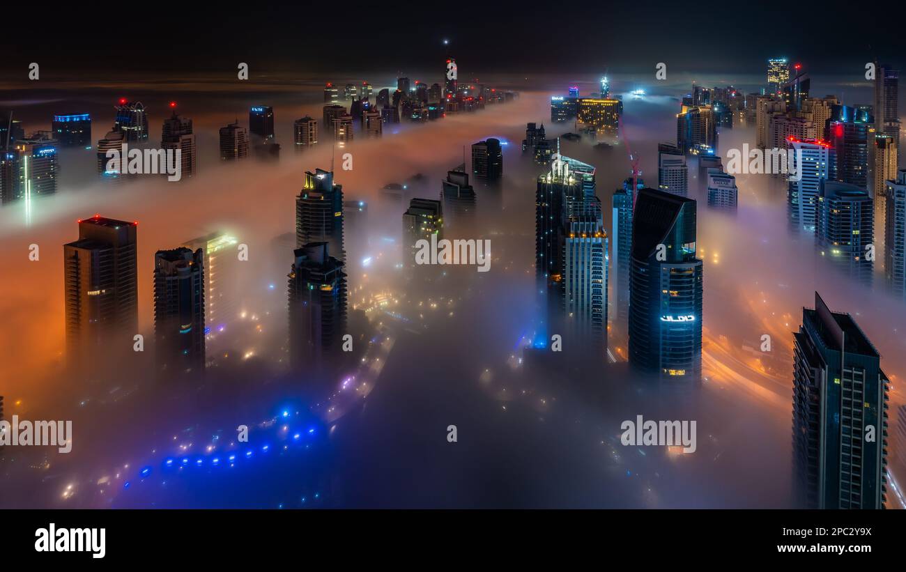 Night shot of the Dubai Marina covered in a thick layer of fog with its ...