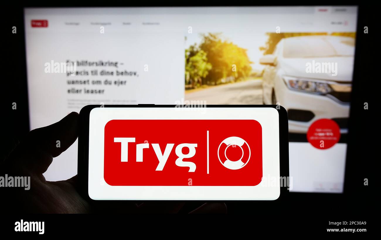 Person holding smartphone with logo of Danish insurance company Tryg ...