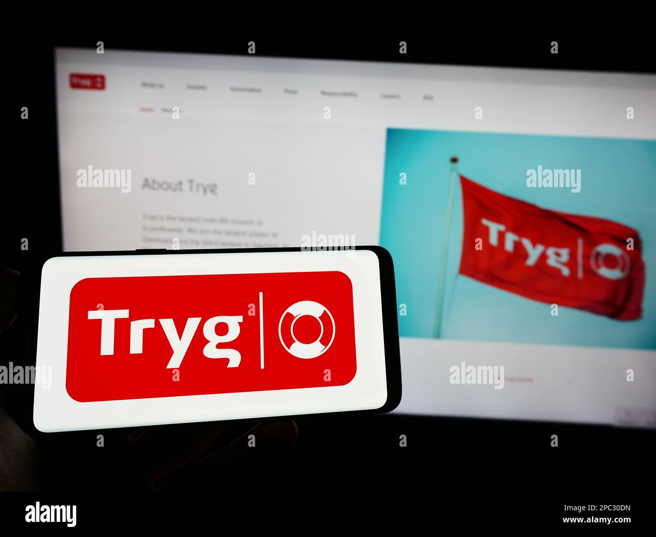 Person holding mobile phone with logo of Danish insurance company Tryg ...