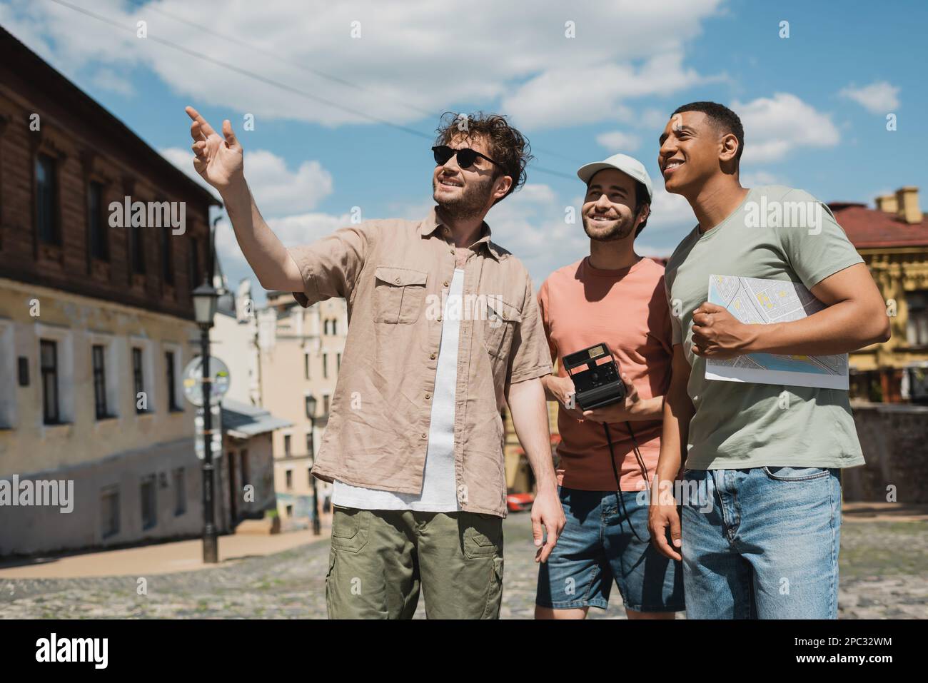 tour guide in sunglasses pointing with hand near multiethnic men with ...