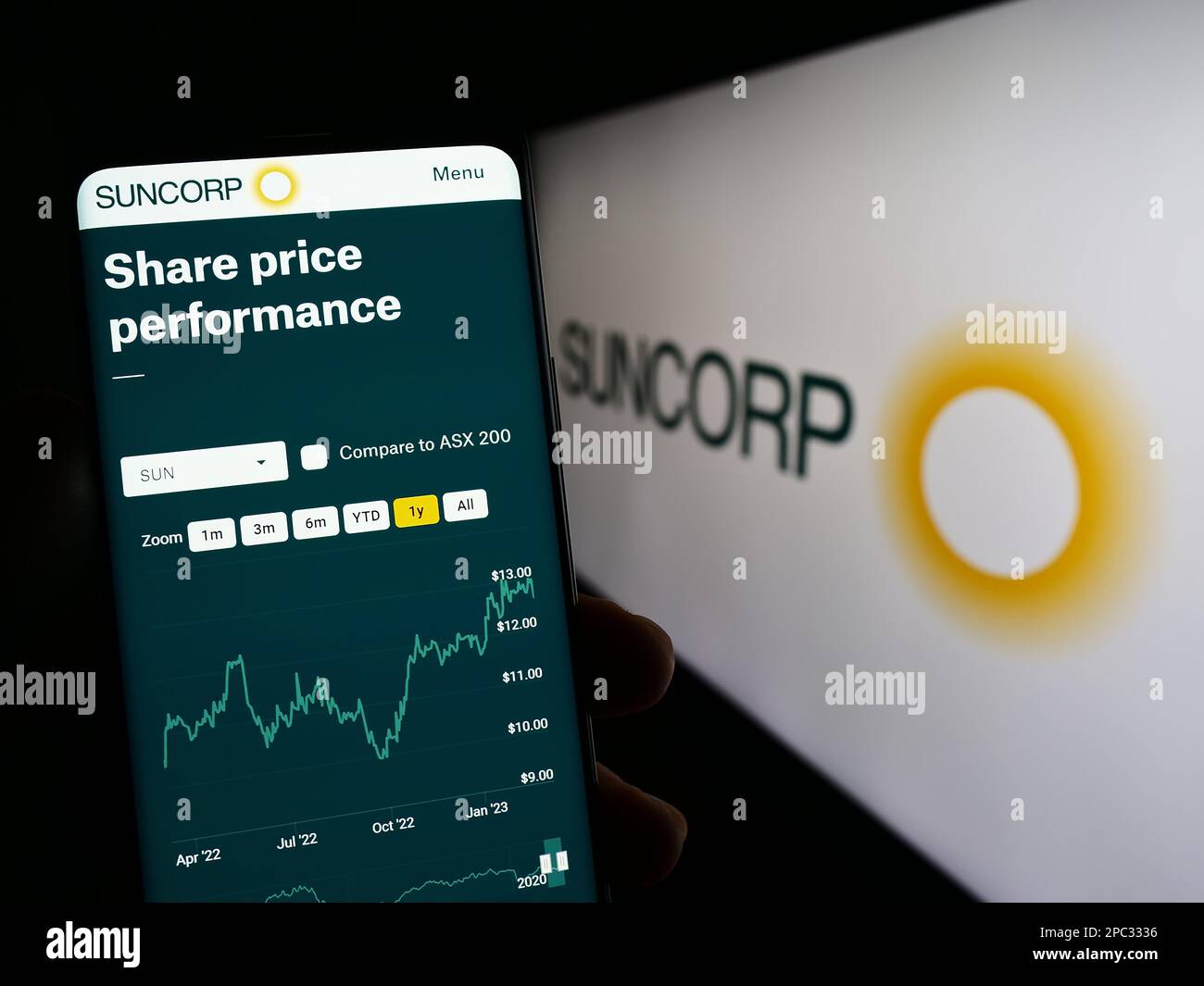 Person holding cellphone with website of Australian insurance Suncorp Group Limited on screen in ...