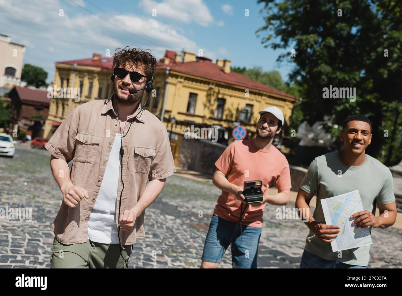 positive multiethnic tourists with vintage camera and map smiling ...