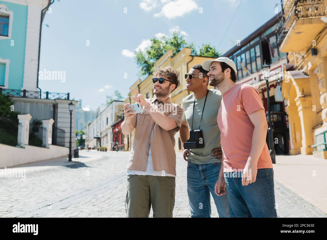 smiling guide with mobile phone pointing with finger while leading tour ...