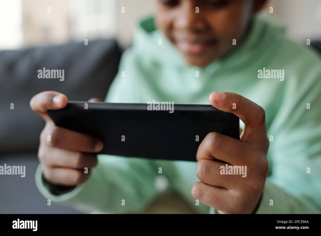 Selective focus on hands of little boy holding mobile phone in front of ...