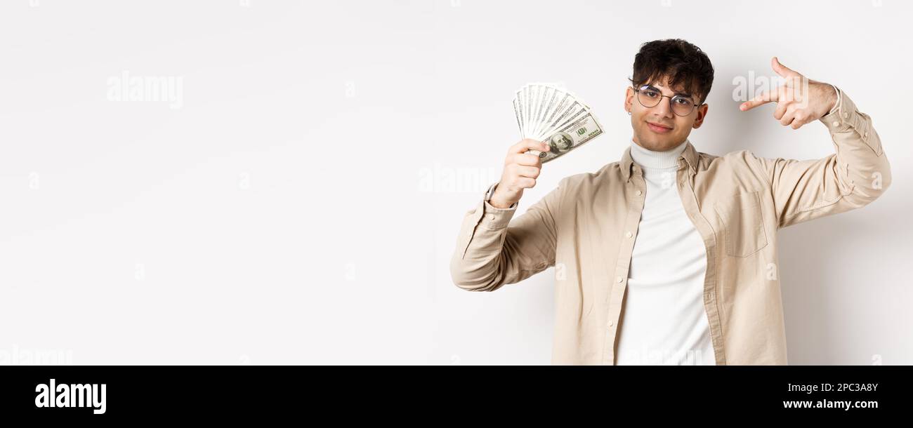Cool handsome guy show-off his income, pointing at dollar bills and ...