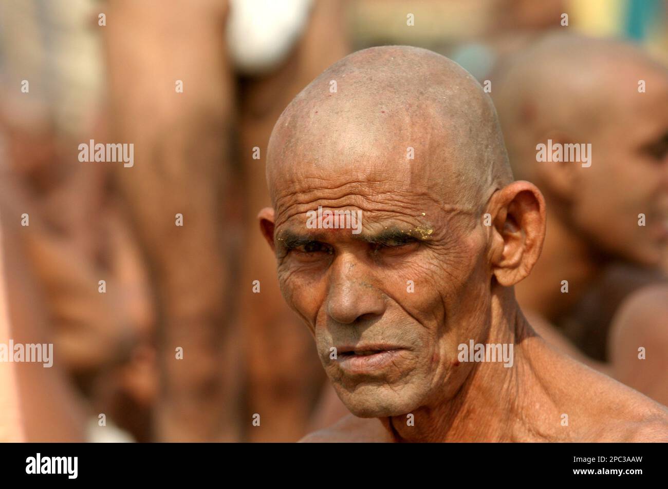 A naga Sadhu or Hindu holyman looks on as he sits on the banks of River ...