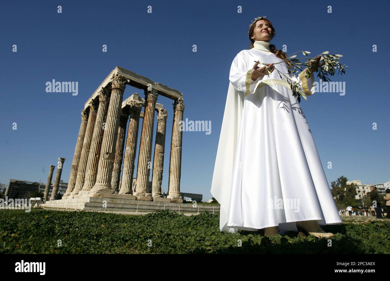 A female priestess holds an olive tree branch as she participates in a ...