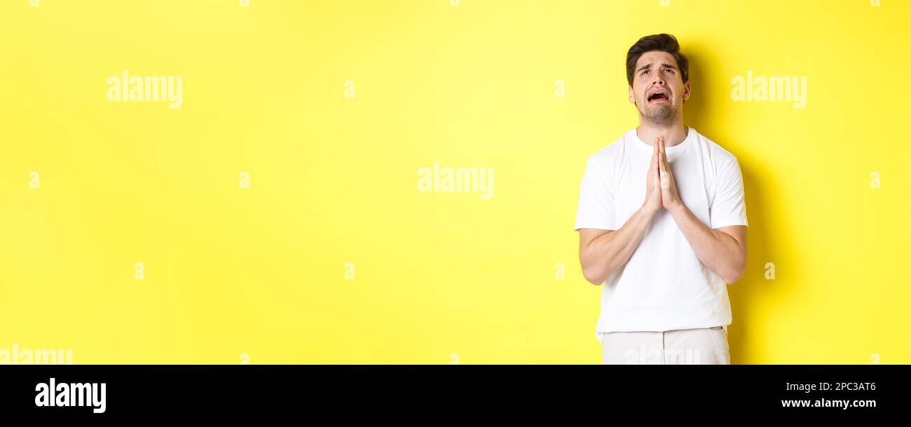 Desperate man pleading God, holding hands in pray and looking up ...
