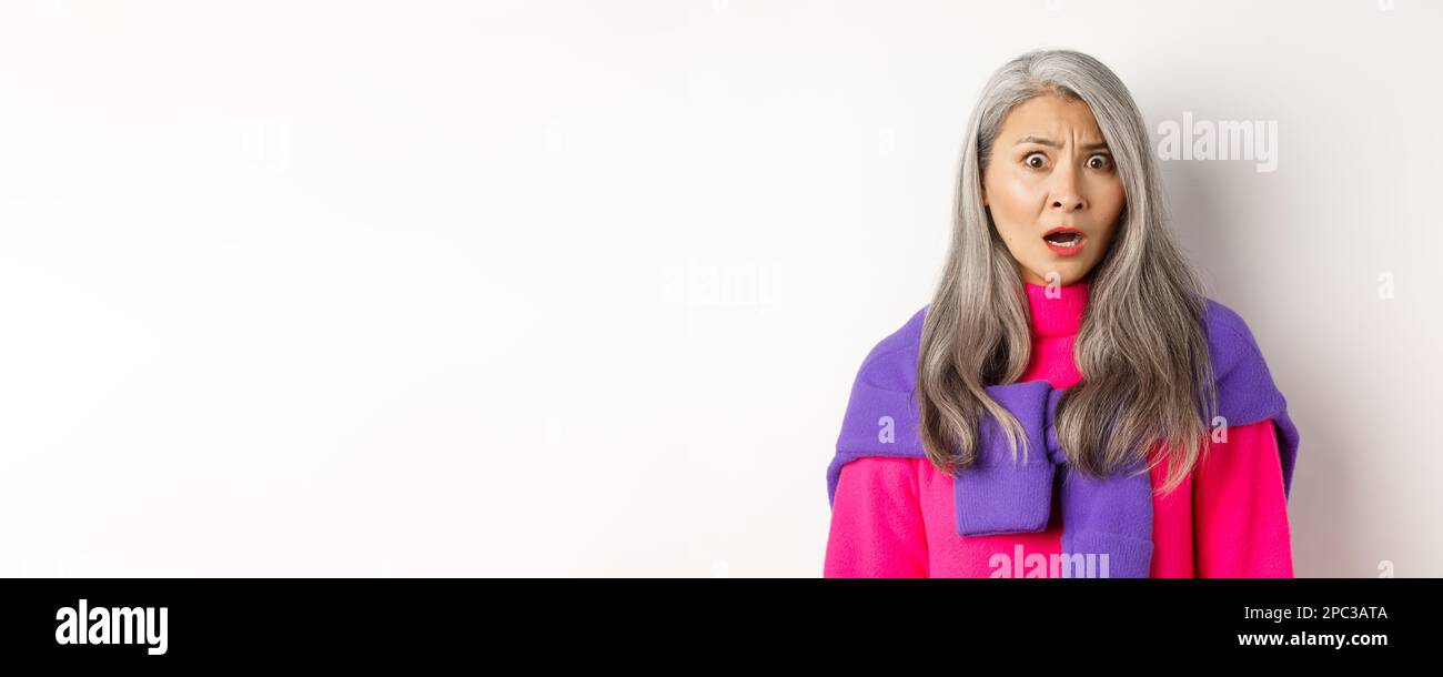 Close-up of shocked asian senior woman gasping, staring with confused ...