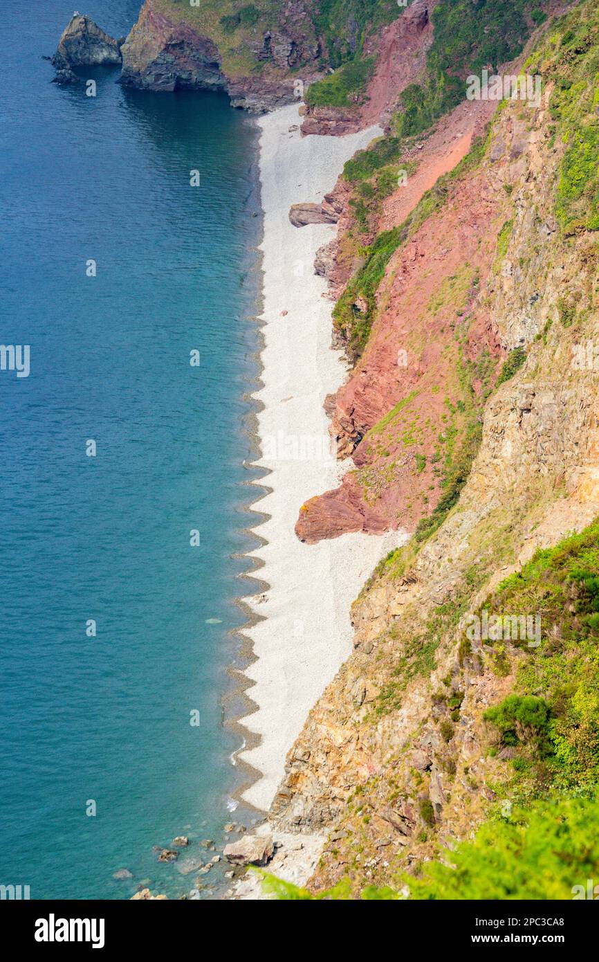 View of sandy beach from above with wave pattern and coloured rocks ...