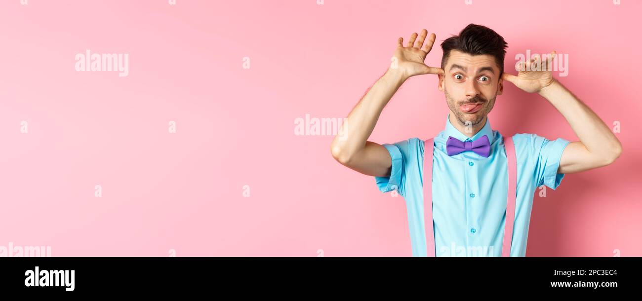 Silly and childish guy in suspenders and bow-tie, mocking someone ...