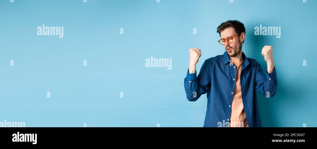 Successful guy dancing and triumphing in new eyewear, raising hands up ...