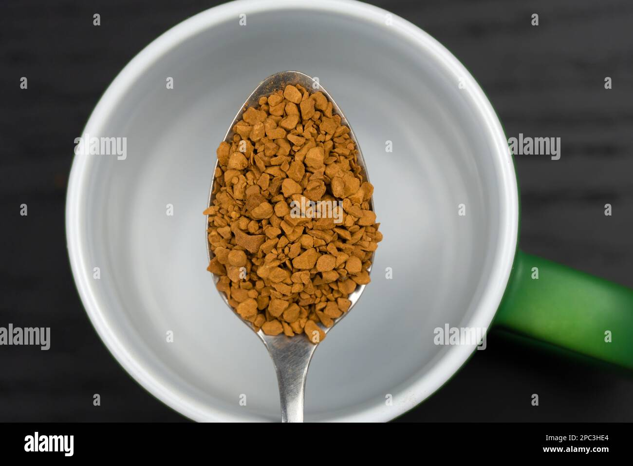 Close-up of a teaspoon with granulated instant coffee over a mug, macro ...