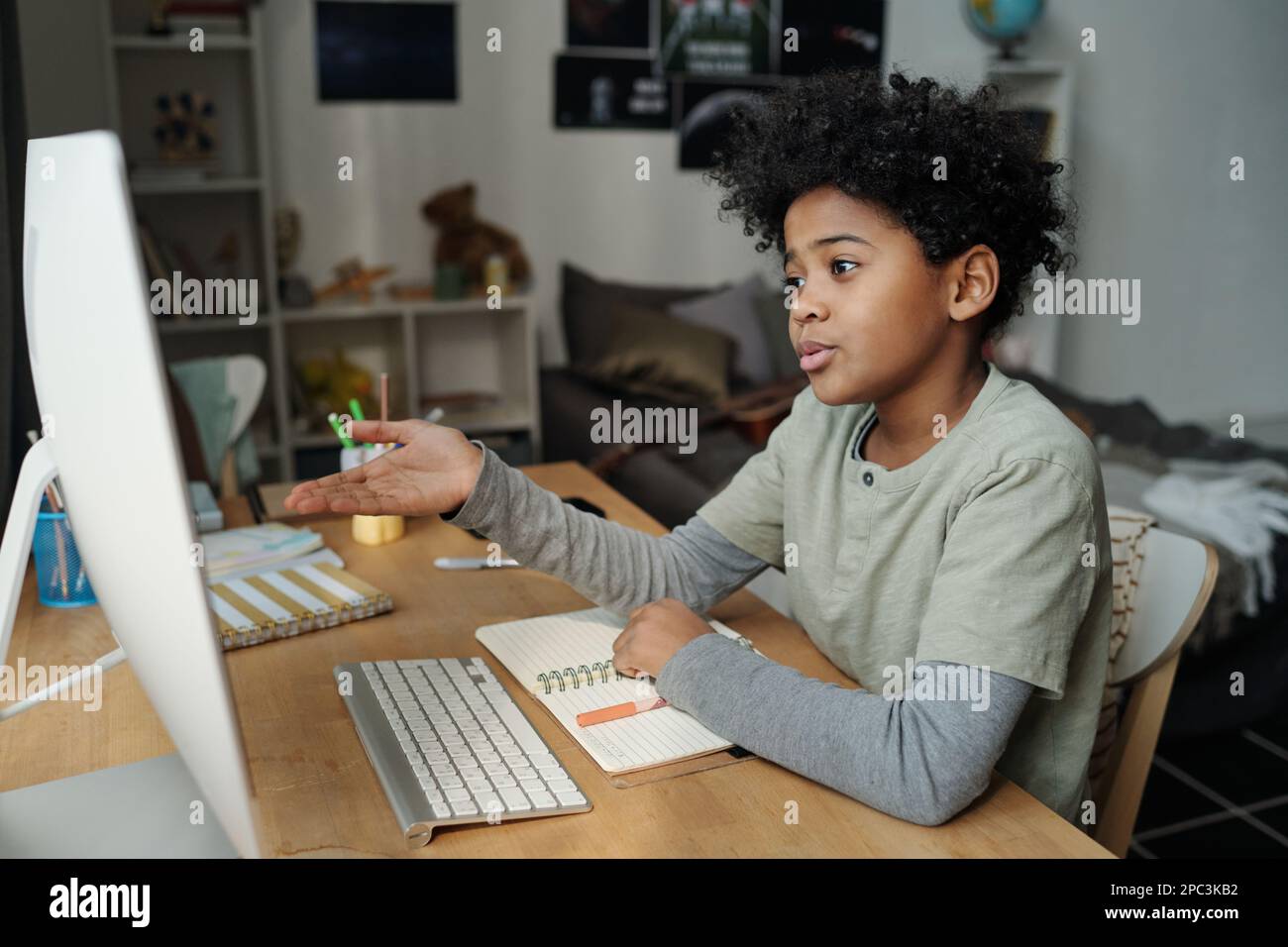Cute schoolboy explaining something during online communication with ...