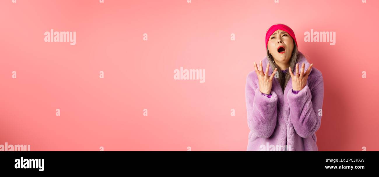 Miserable asian senior woman in stylish purple faux fur coat, pleading ...