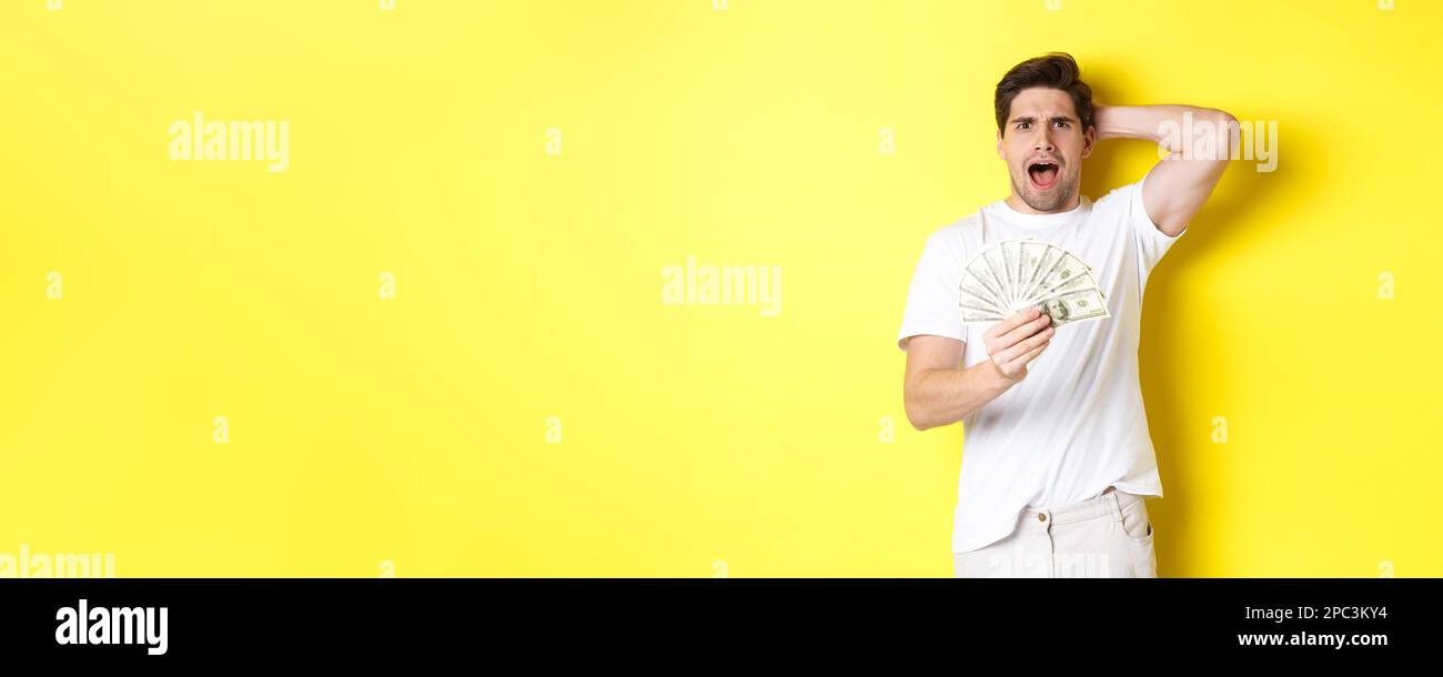 Frustrated man holding money, shouting and panicking, standing over ...