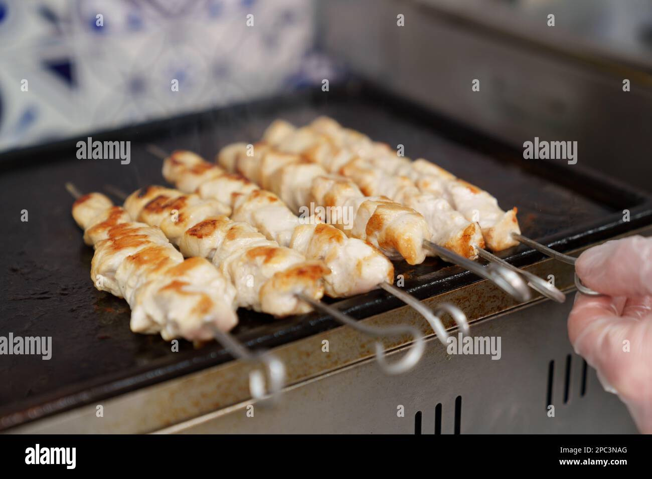 The cook turning chicken meat on skewers. Chef preparing marinated ...