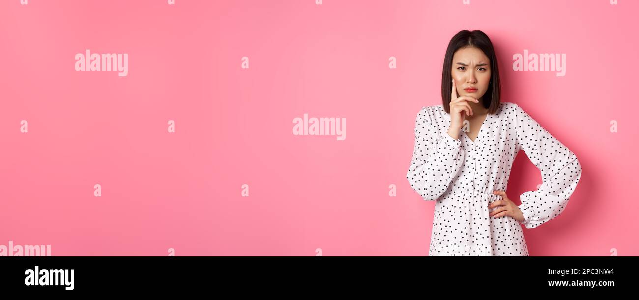 Concerned asian woman staring at camera suspicious, having doubts ...