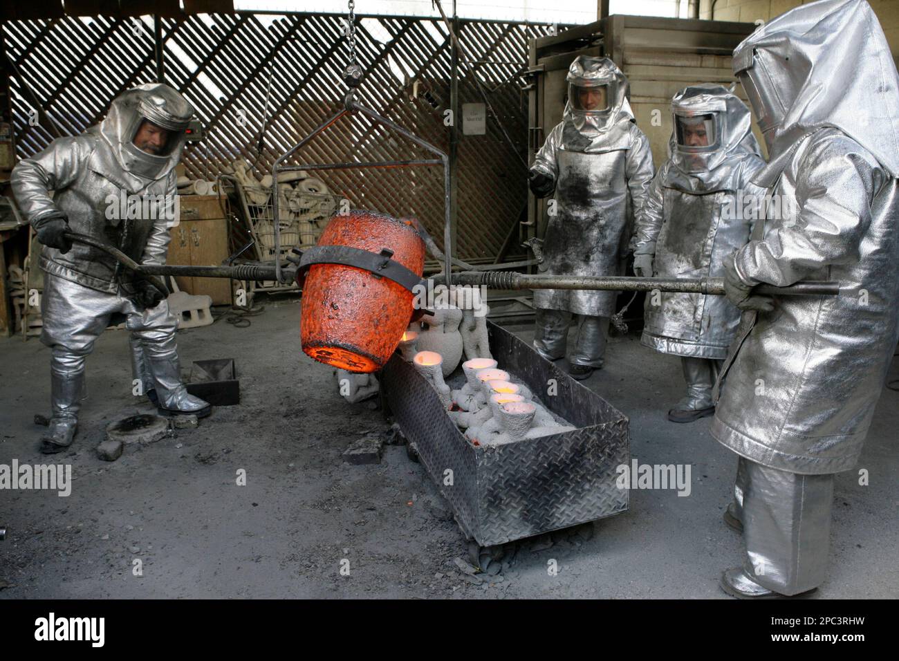 Workers at the American Fine Arts Foundry pour molten bronze into molds ...