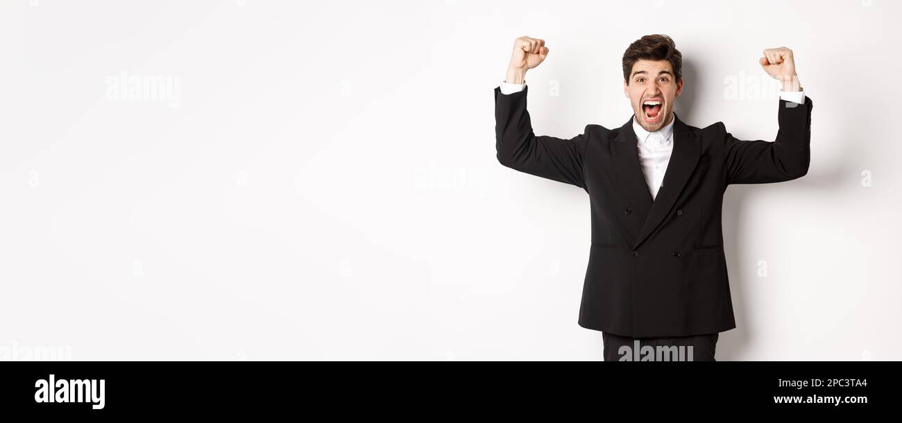 Successful handsome businessman triumphing, raising hands up and ...