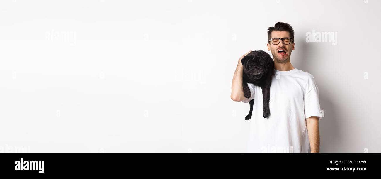 Sad dog owner crying, holding cute black pug on shoulder and looking ...