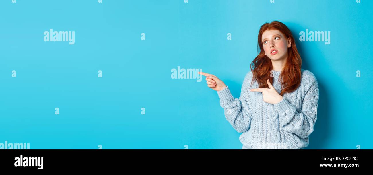 Annoyed teenage redhead girl roll eyes, pointing fingers left at ...