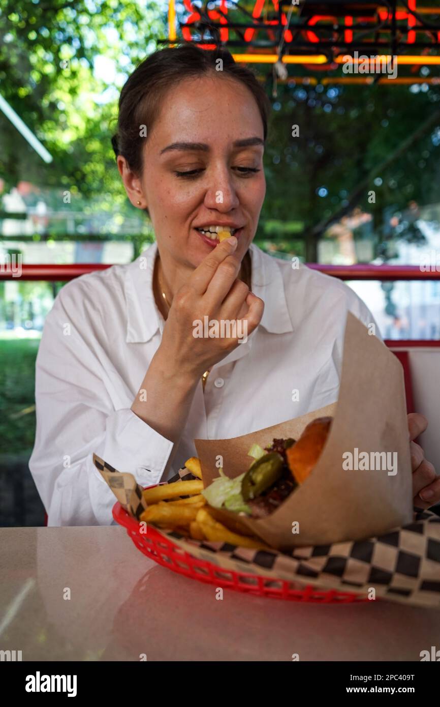 Young woman eating burger fries hi-res stock photography and images - Alamy
