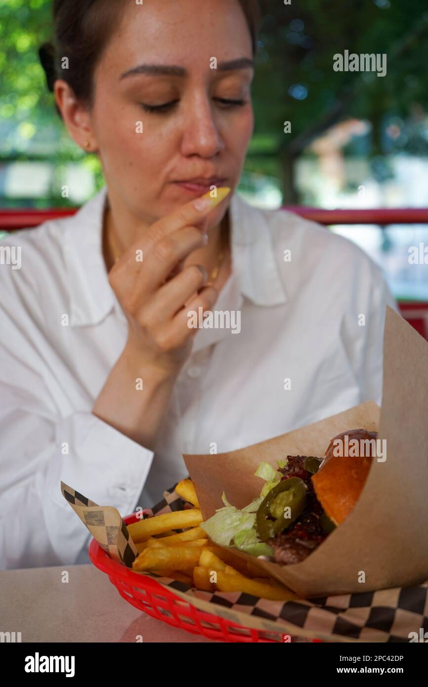 Young woman eating burger fries hi-res stock photography and images - Alamy
