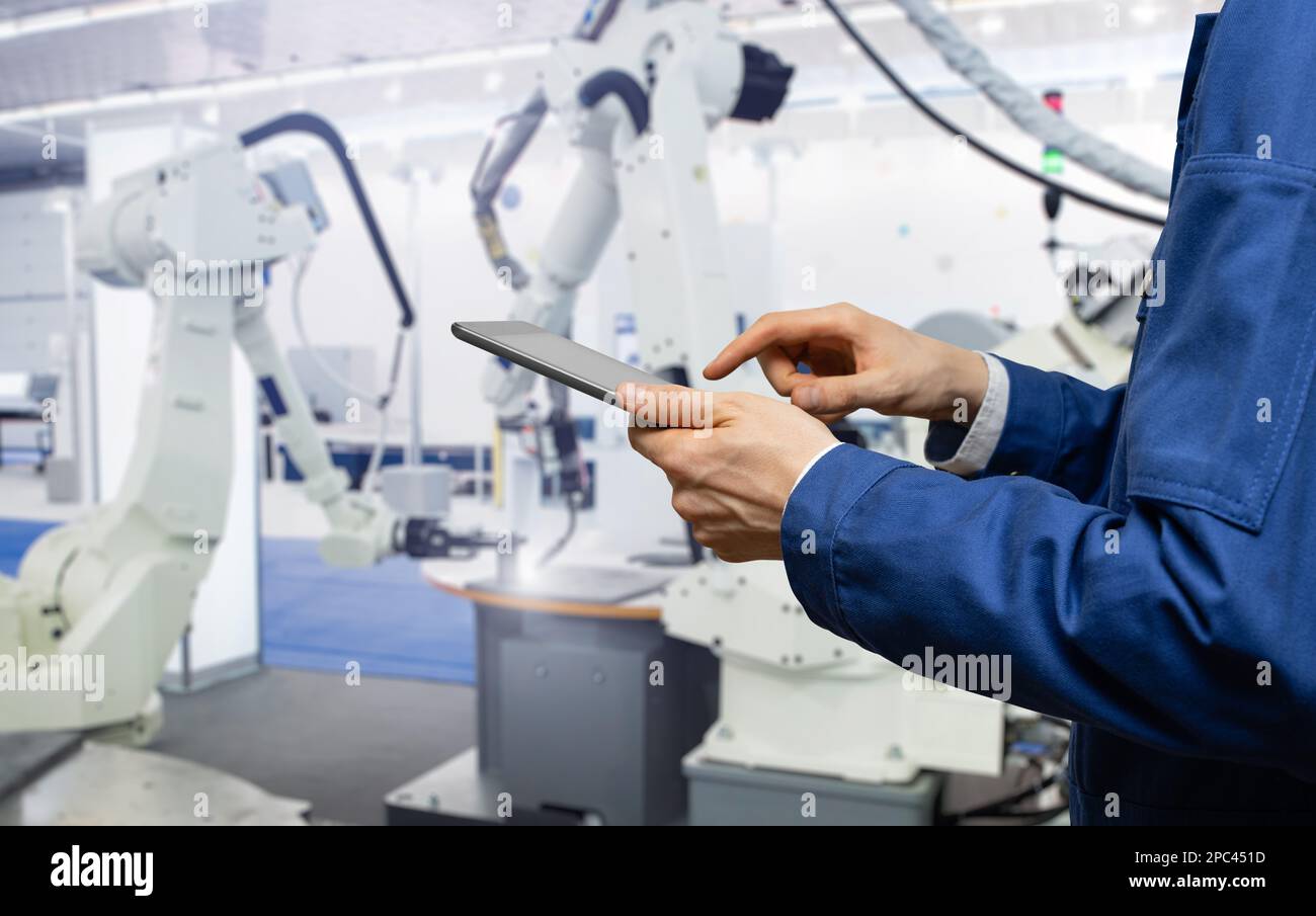 Engineer uses a digital tablet to control robots in a smart factory ...