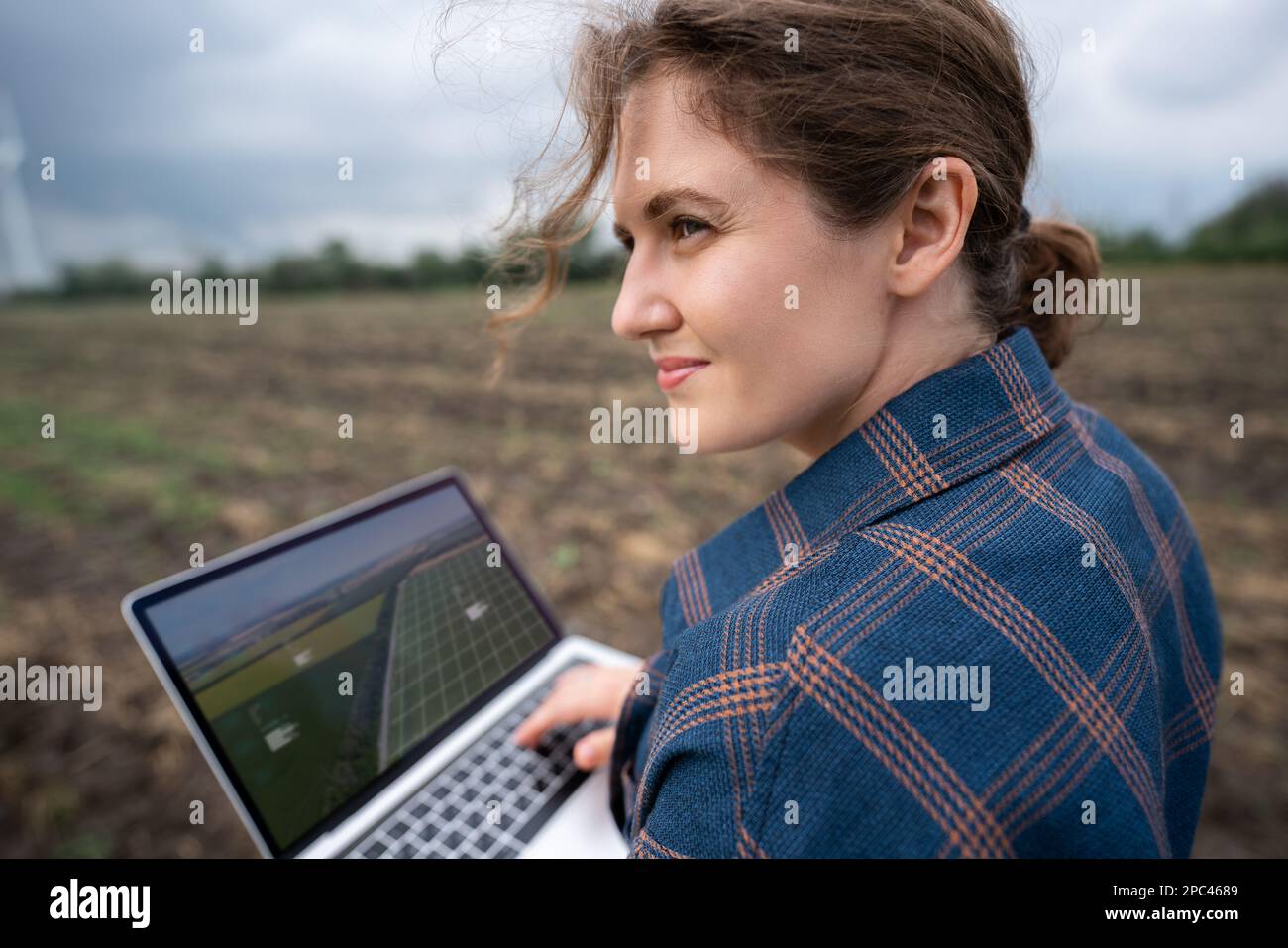 Farmer with laptop on the field. Wind turbines on a horizon. Smart ...