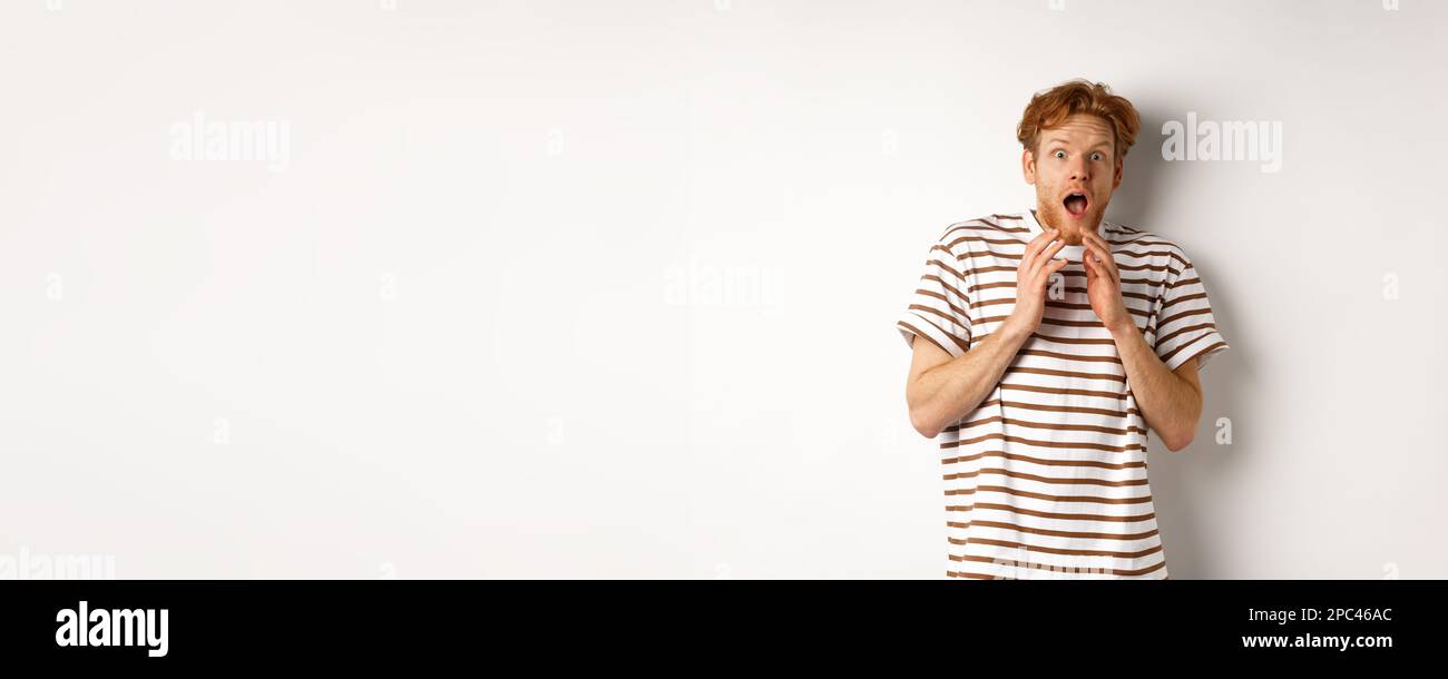Timid young man with red hair, looking scared, jumping and screaming ...